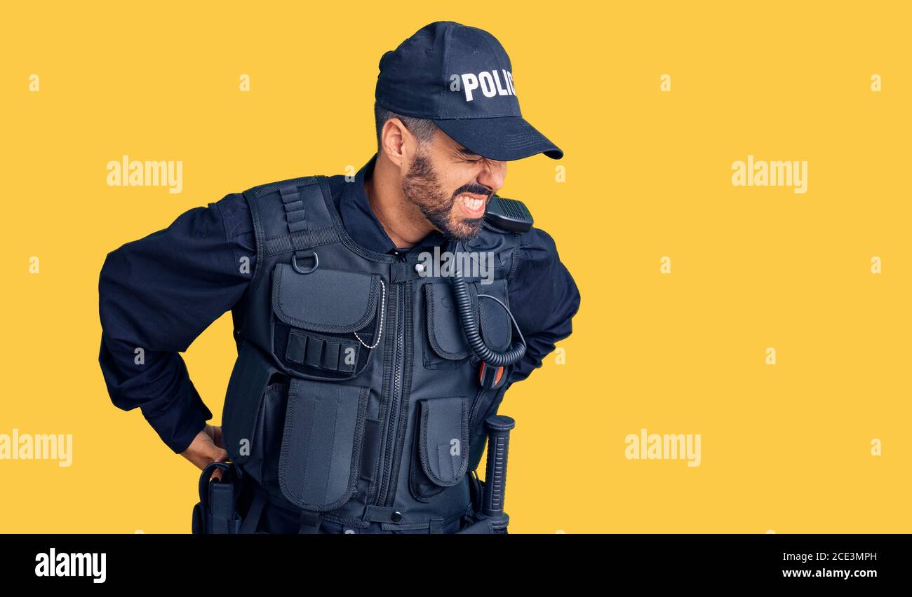 Young hispanic man wearing police uniform suffering of backache ...