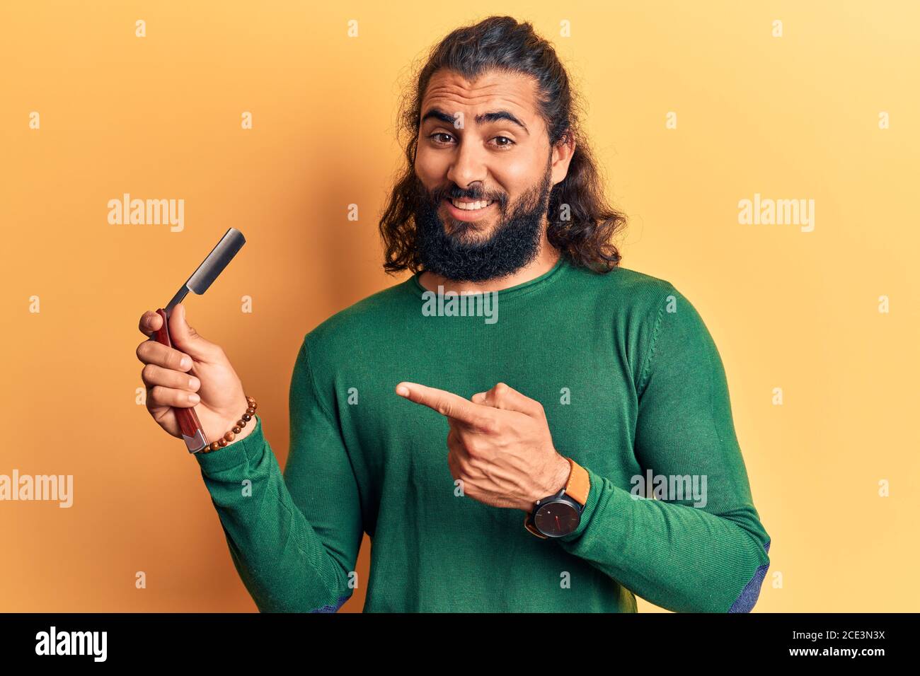 Young arab man holding barber razor smiling happy pointing with hand ...
