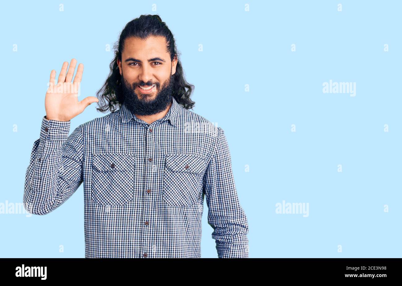 Young arab man wearing casual clothes waiving saying hello happy and ...