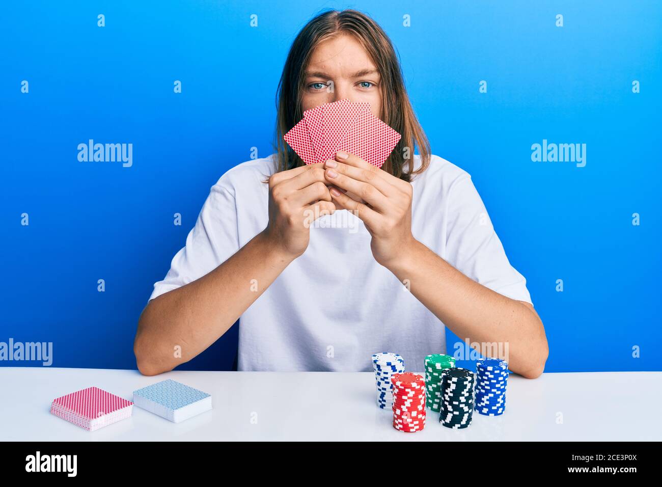 Handsome caucasian man with long hair playing gambling poker covering ...