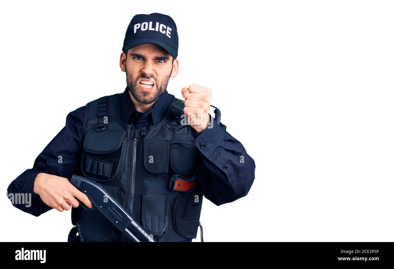 Young handsome man with beard wearing police uniform holding shotgun ...