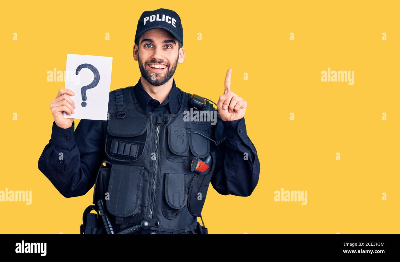 Young handsome man with beard wearing police uniform holding question ...