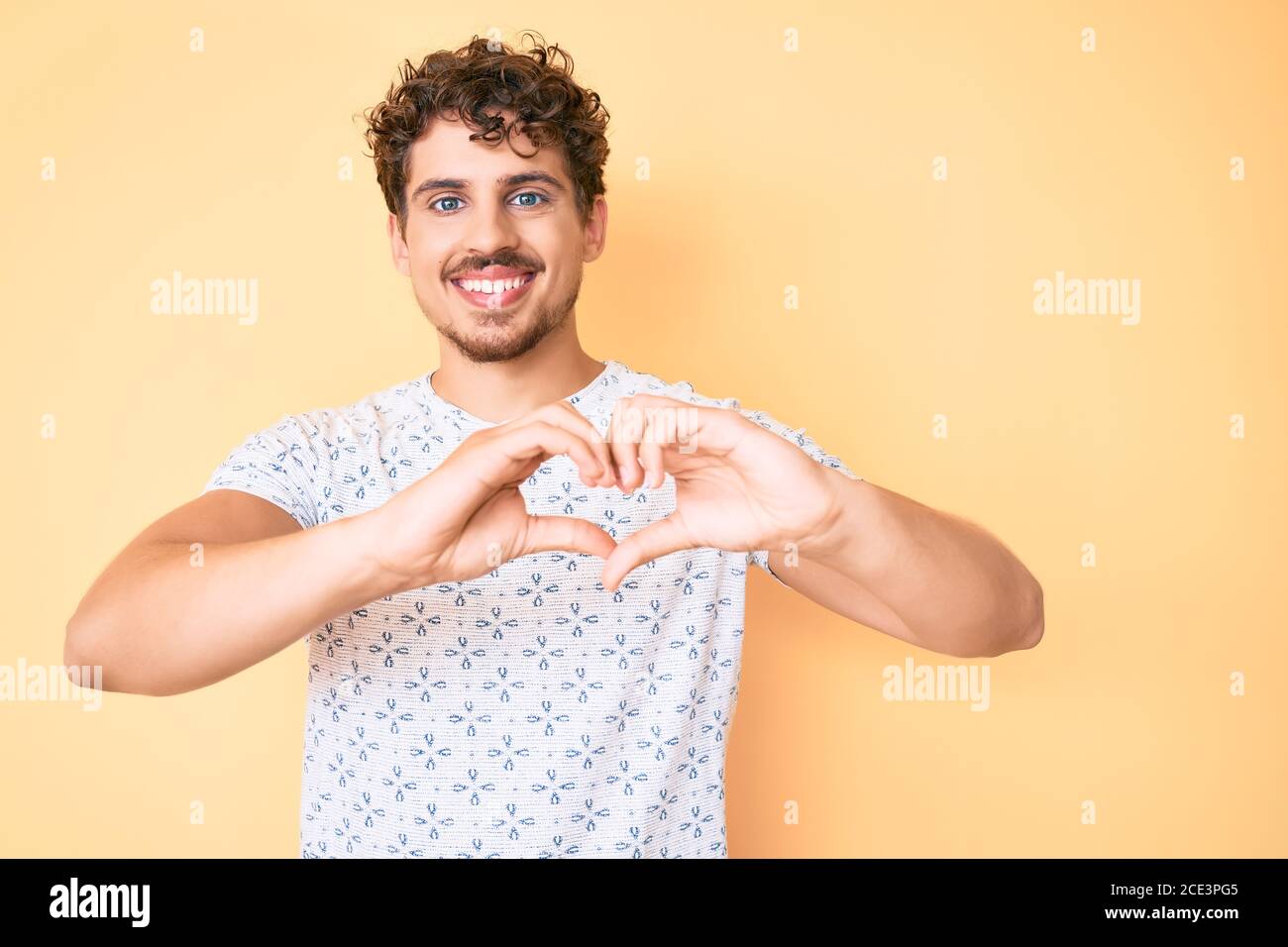 Young caucasian man with curly hair wearing casual clothes smiling in ...