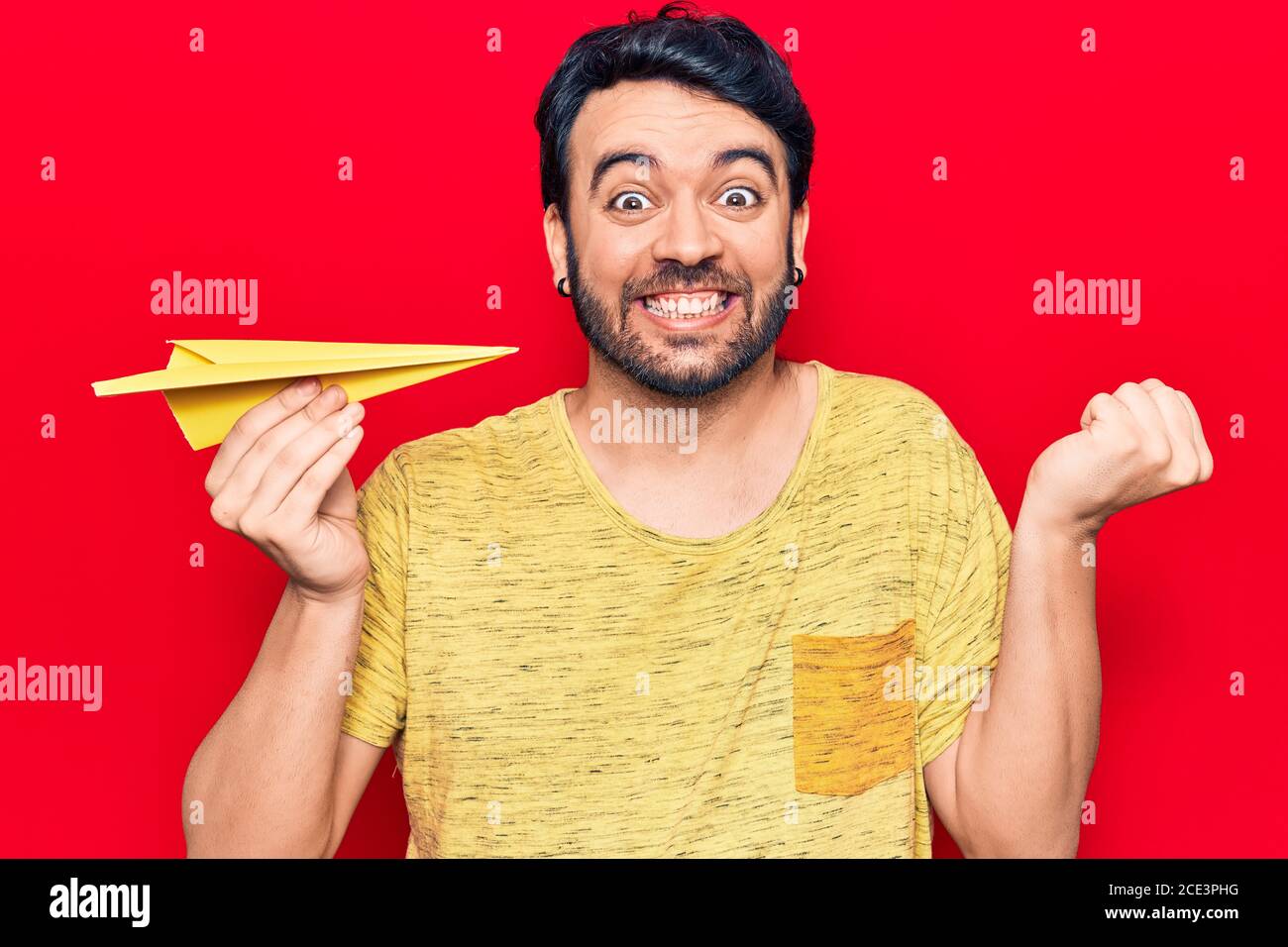 Young hispanic man holding paper airplane screaming proud, celebrating ...