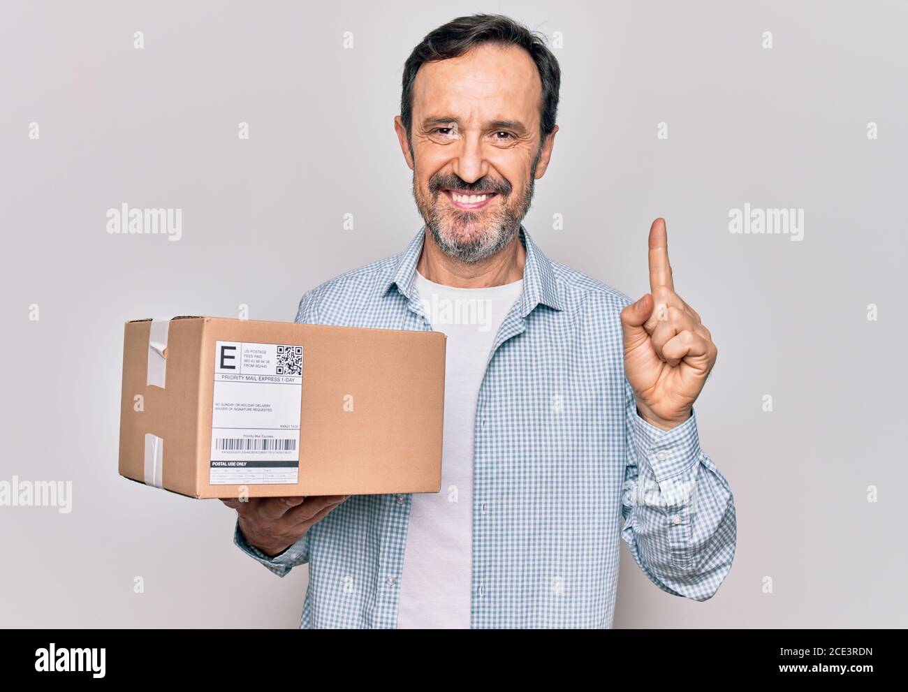 Middle age handsome man holding package over isolated white backgrounds ...