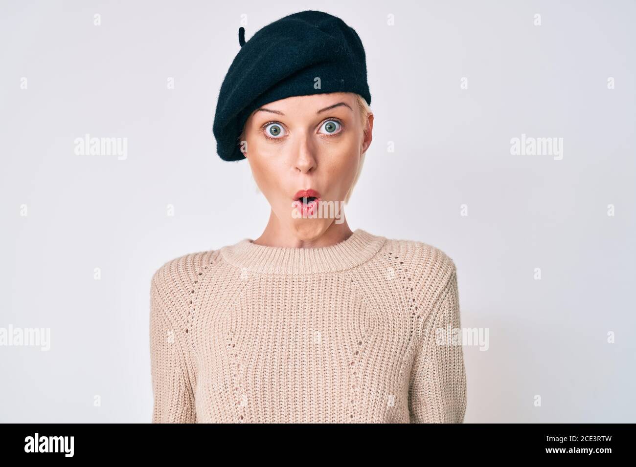 Young blonde woman wearing french look with beret scared and amazed ...