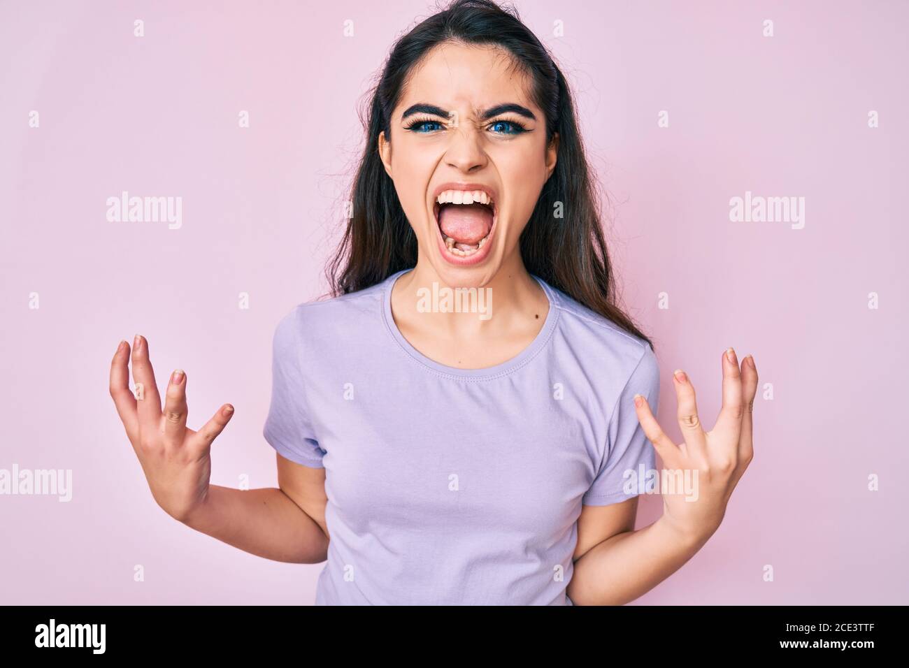 Brunette teenager girl wearing casual clothes crazy and mad shouting ...