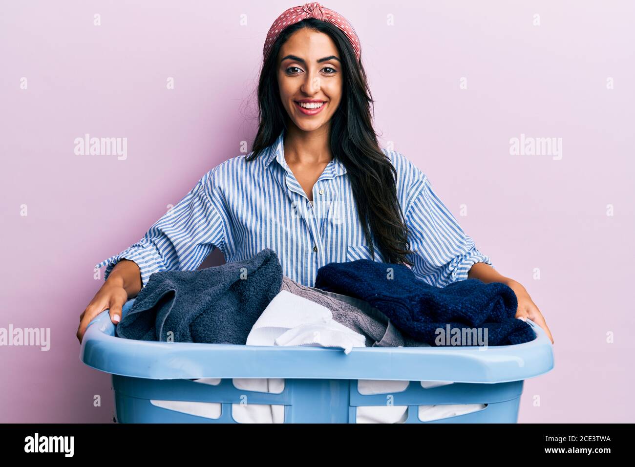 Beautiful hispanic woman holding laundry basket smiling and laughing ...