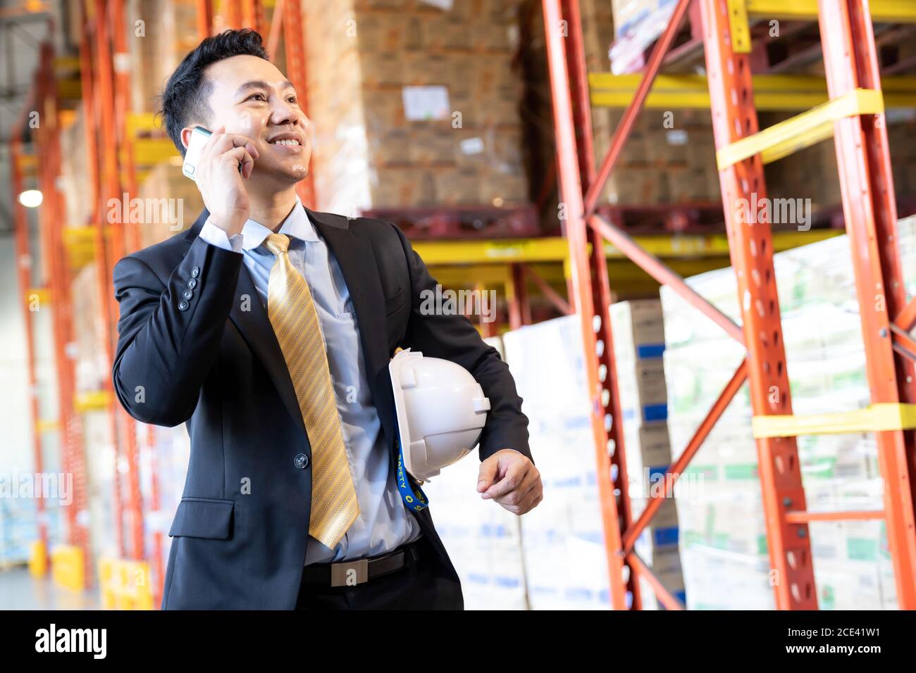 Portrait asian businessman making a call in distribution warehouse ...
