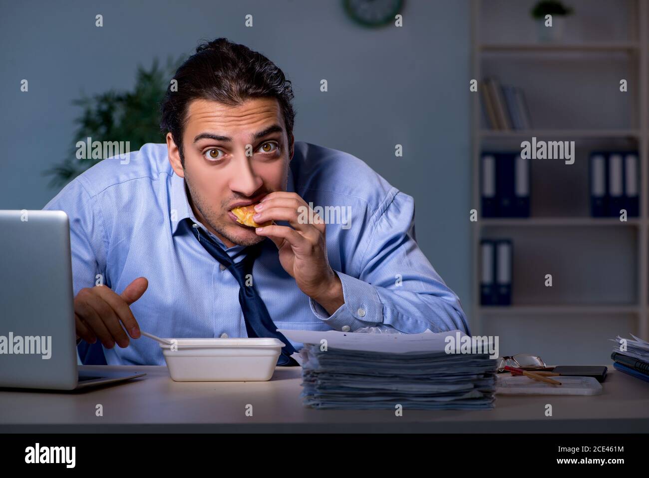 Hungry employee working late in office Stock Photo - Alamy