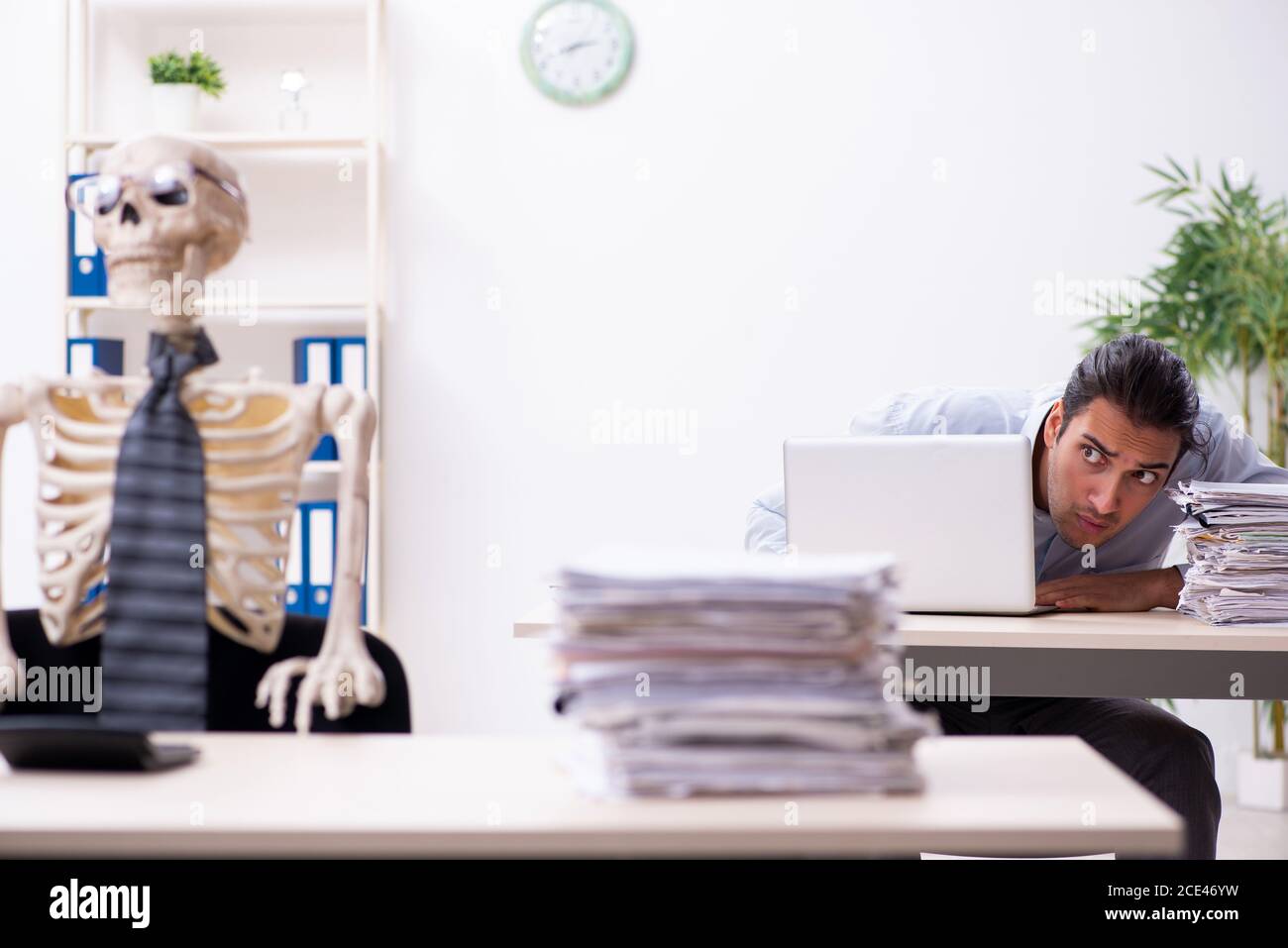 Young employee and skeleton in the office Stock Photo - Alamy