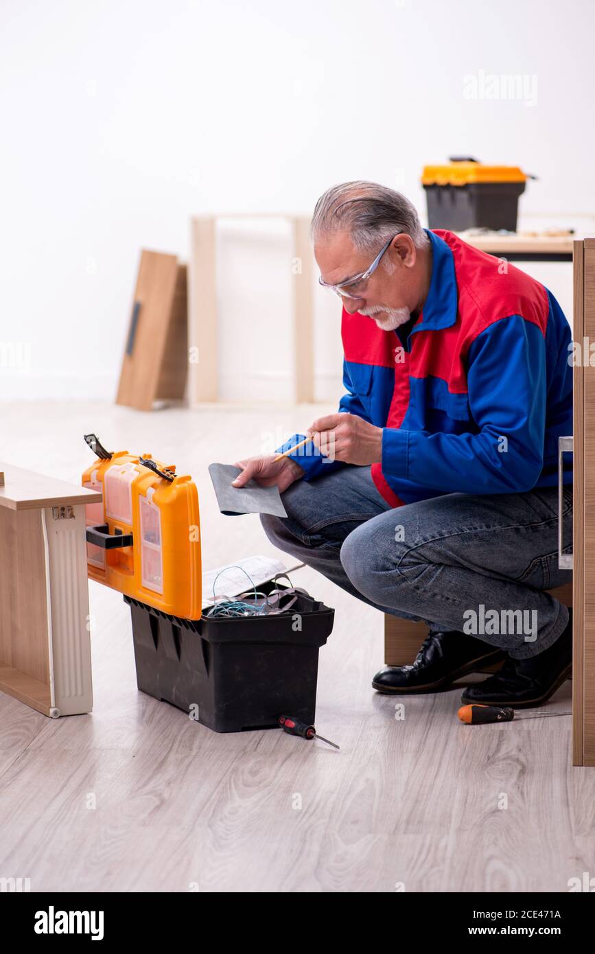Old carpenter working indoors on furniture Stock Photo - Alamy