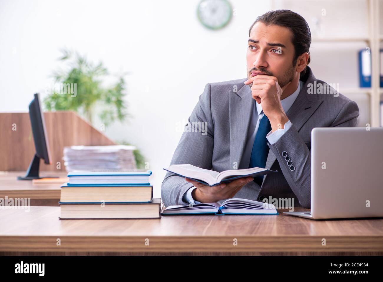 Young businessman reading books at workplace Stock Photo - Alamy