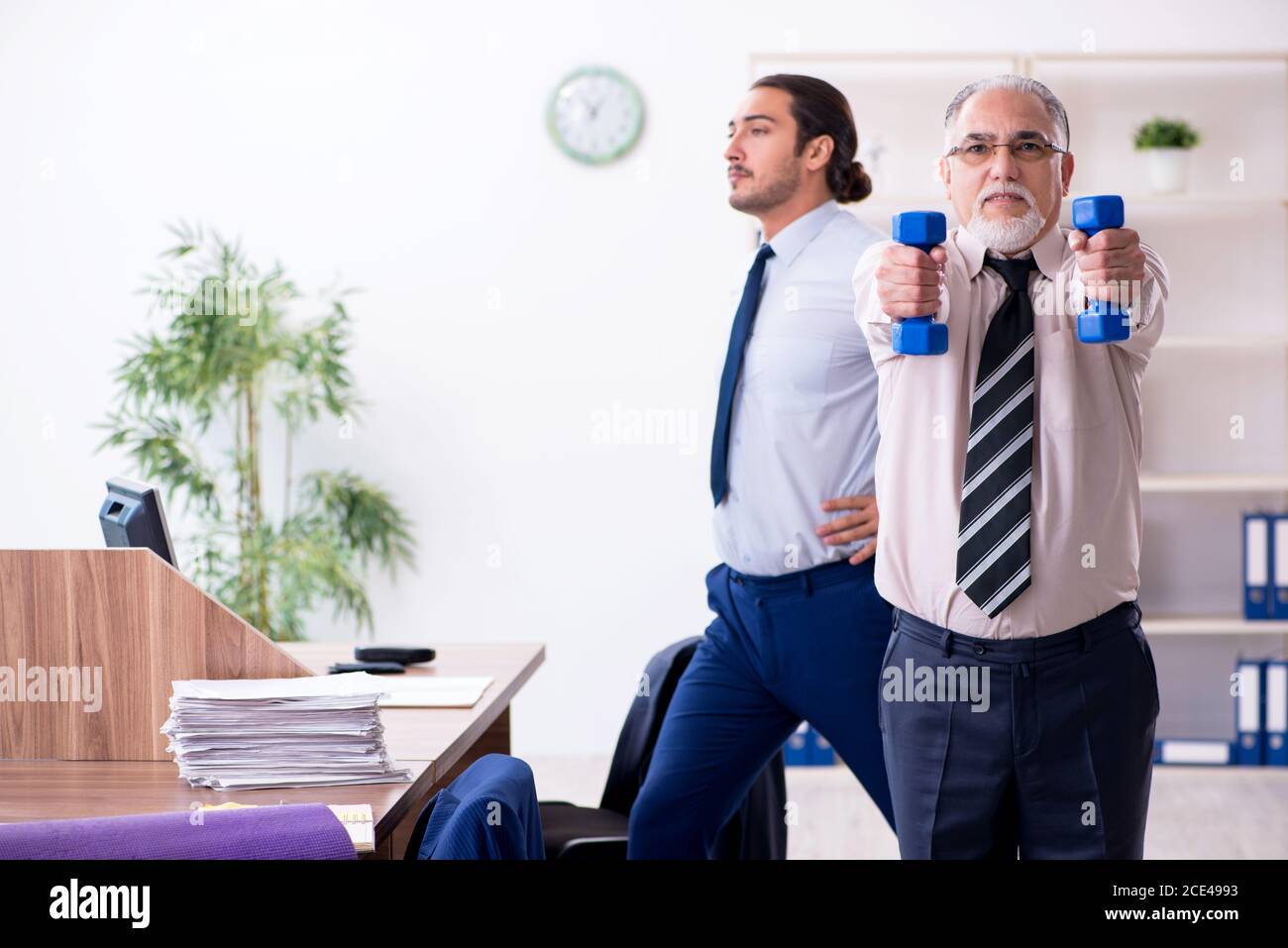 Two employees doing physical exercises at the workplace Stock Photo - Alamy