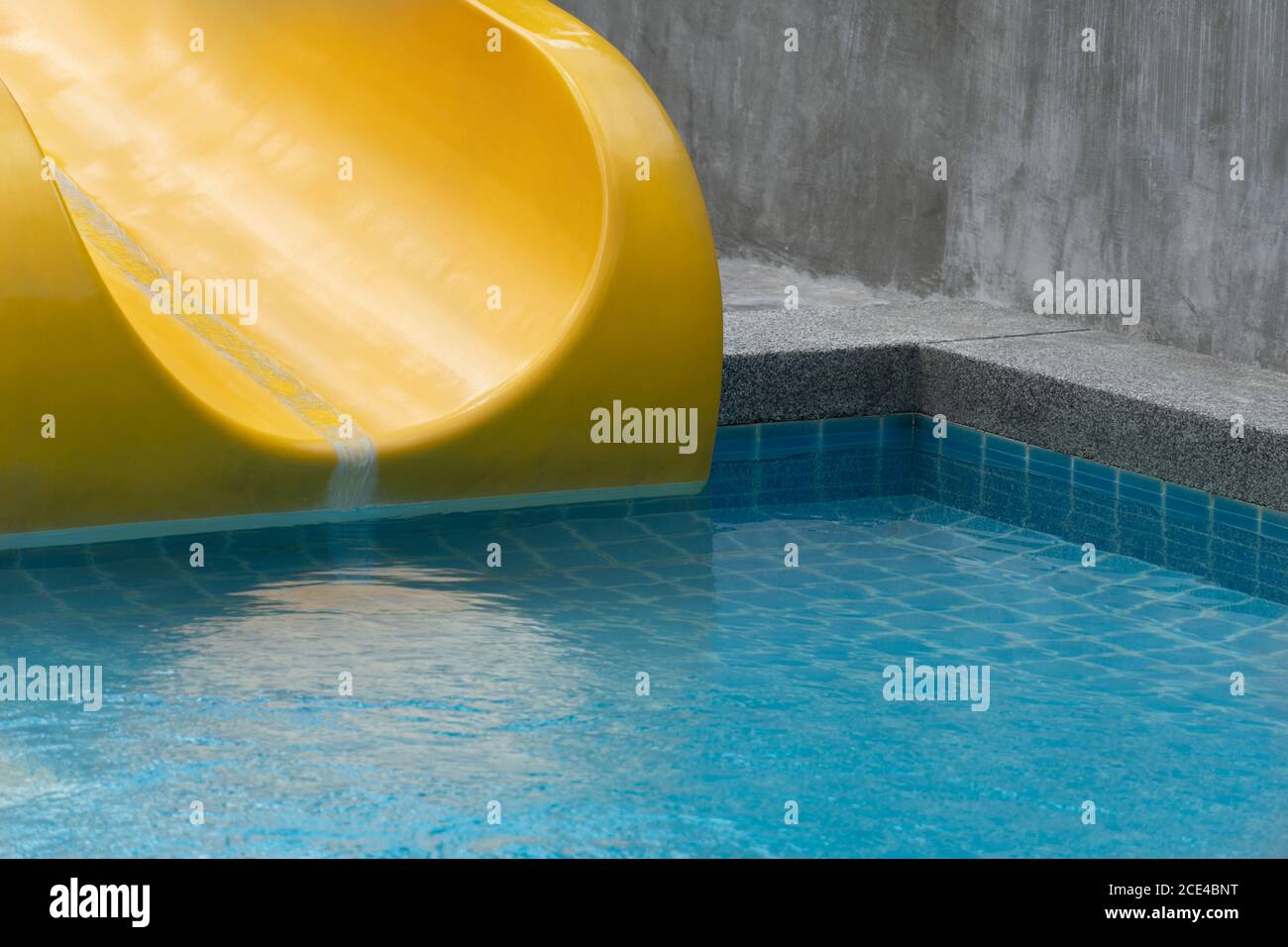 colorful yellow slider with blue swimming pool in summer time ...