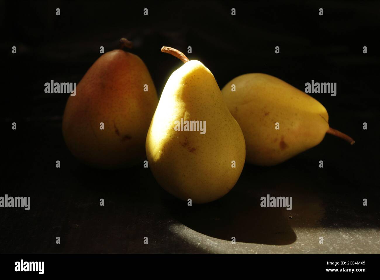 Three yellow seasonal pears on a black background Stock Photo - Alamy