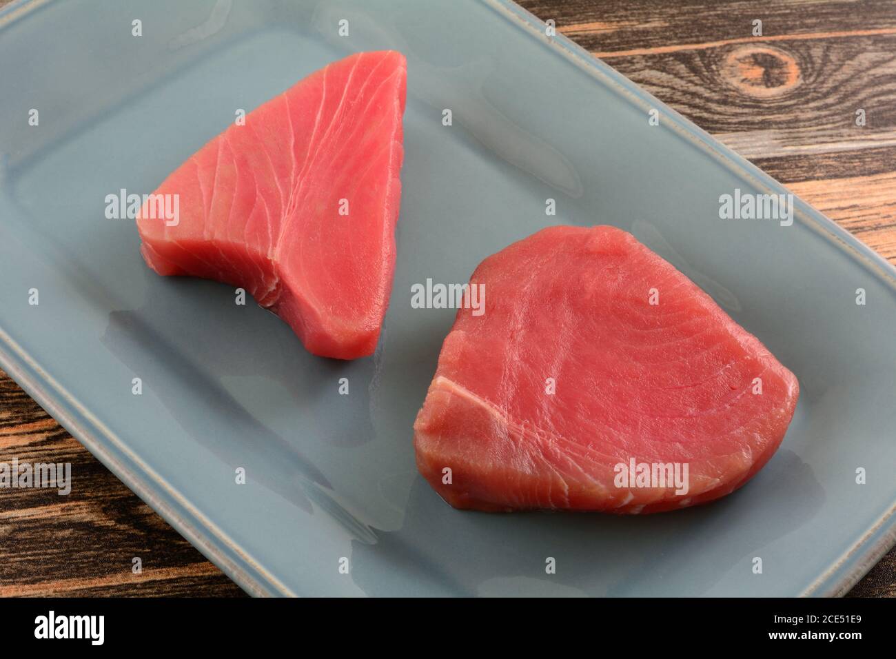 Two fresh raw wild caught tuna fish fillets on blue plate in ...