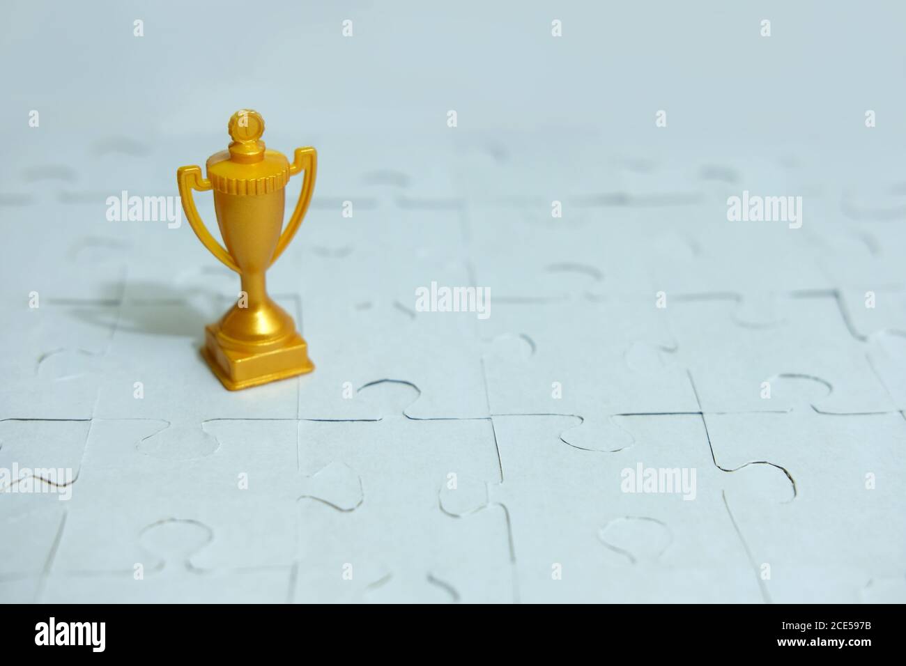 a golden trophy stands between a pile of puzzles Stock Photo - Alamy