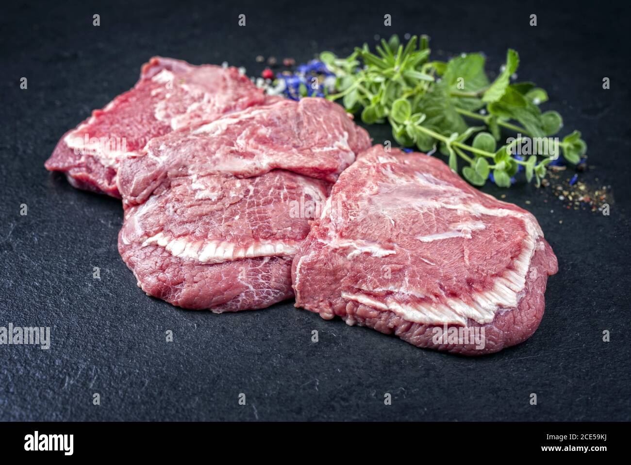 Traditional German raw beef cheeks offered as closeup on a black board ...