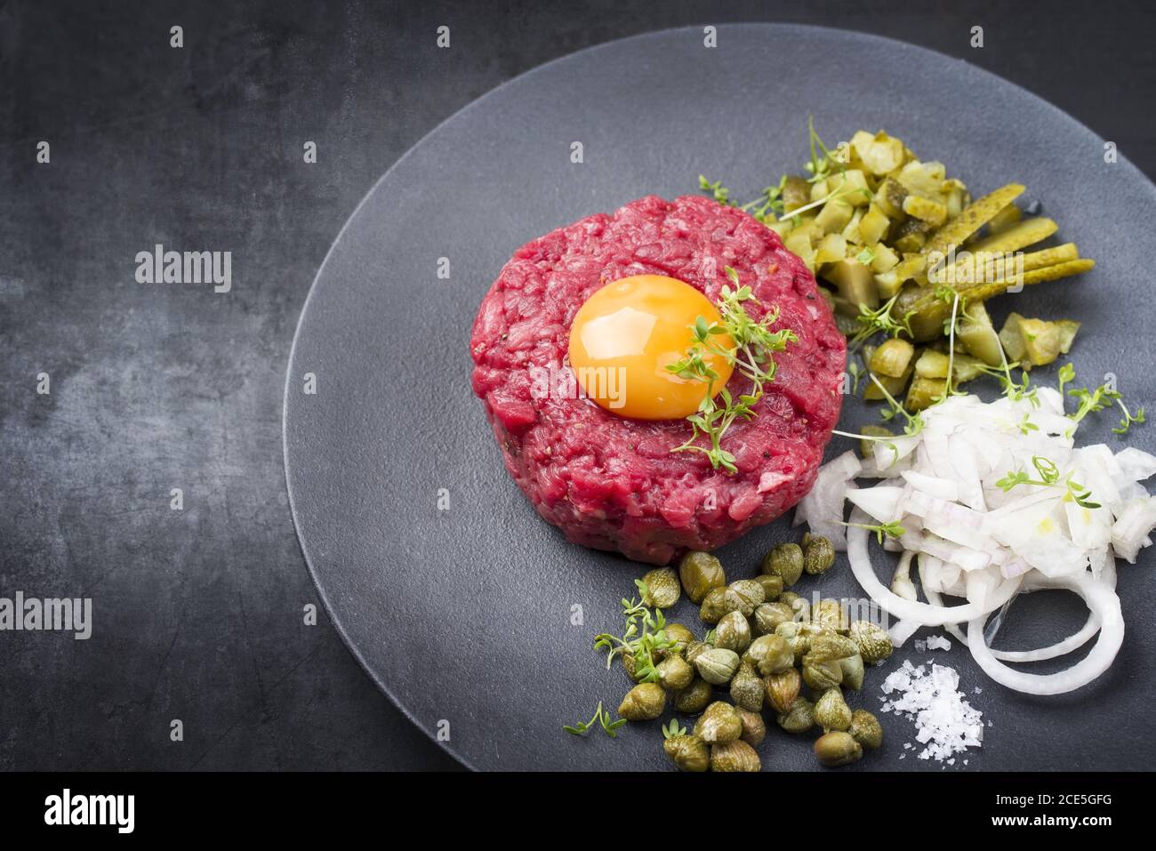 Gourmet tartar raw from beef fillet with yellow of the egg and gherkin ...
