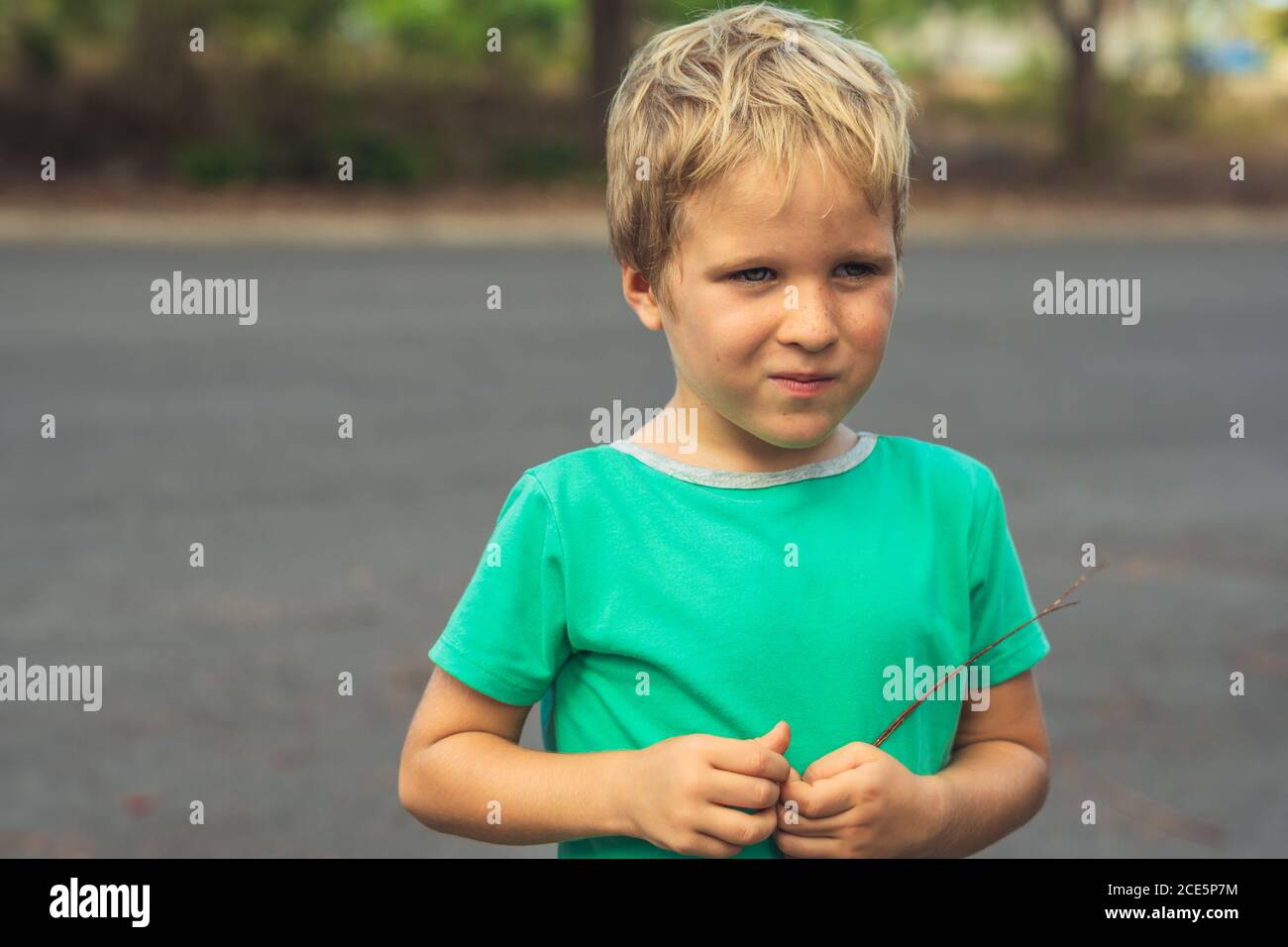 Funny mischievous cute blond boy with freckled face restrained smile ...