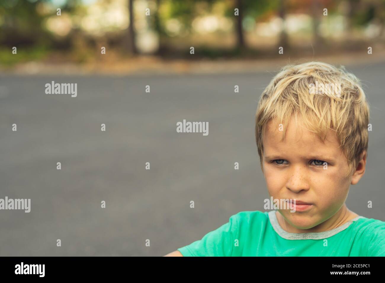 Portrait handsome cute serious sad blond boy in bad mood look away ...