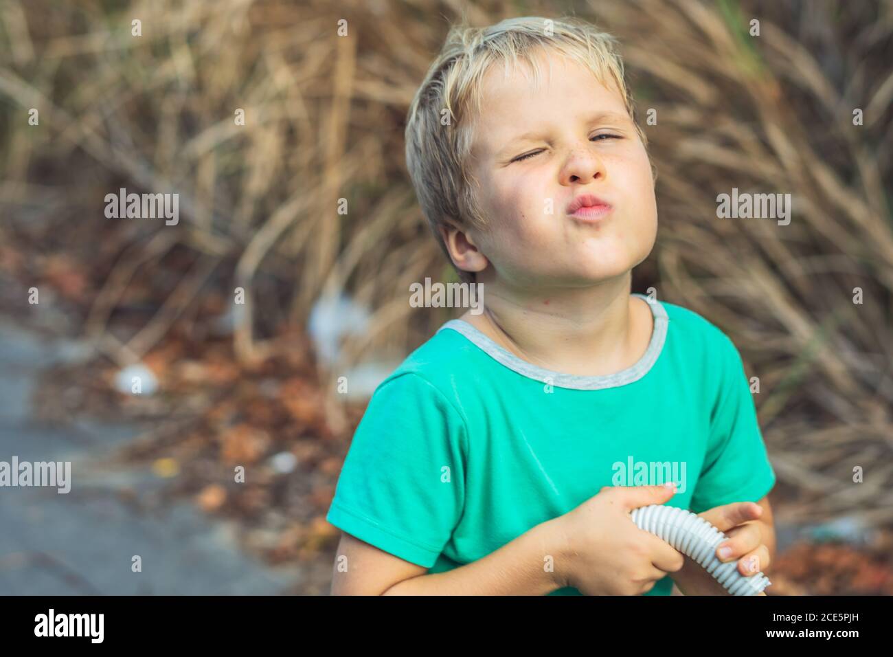Funny mischievous cute blond boy making freckles face showing love kiss ...