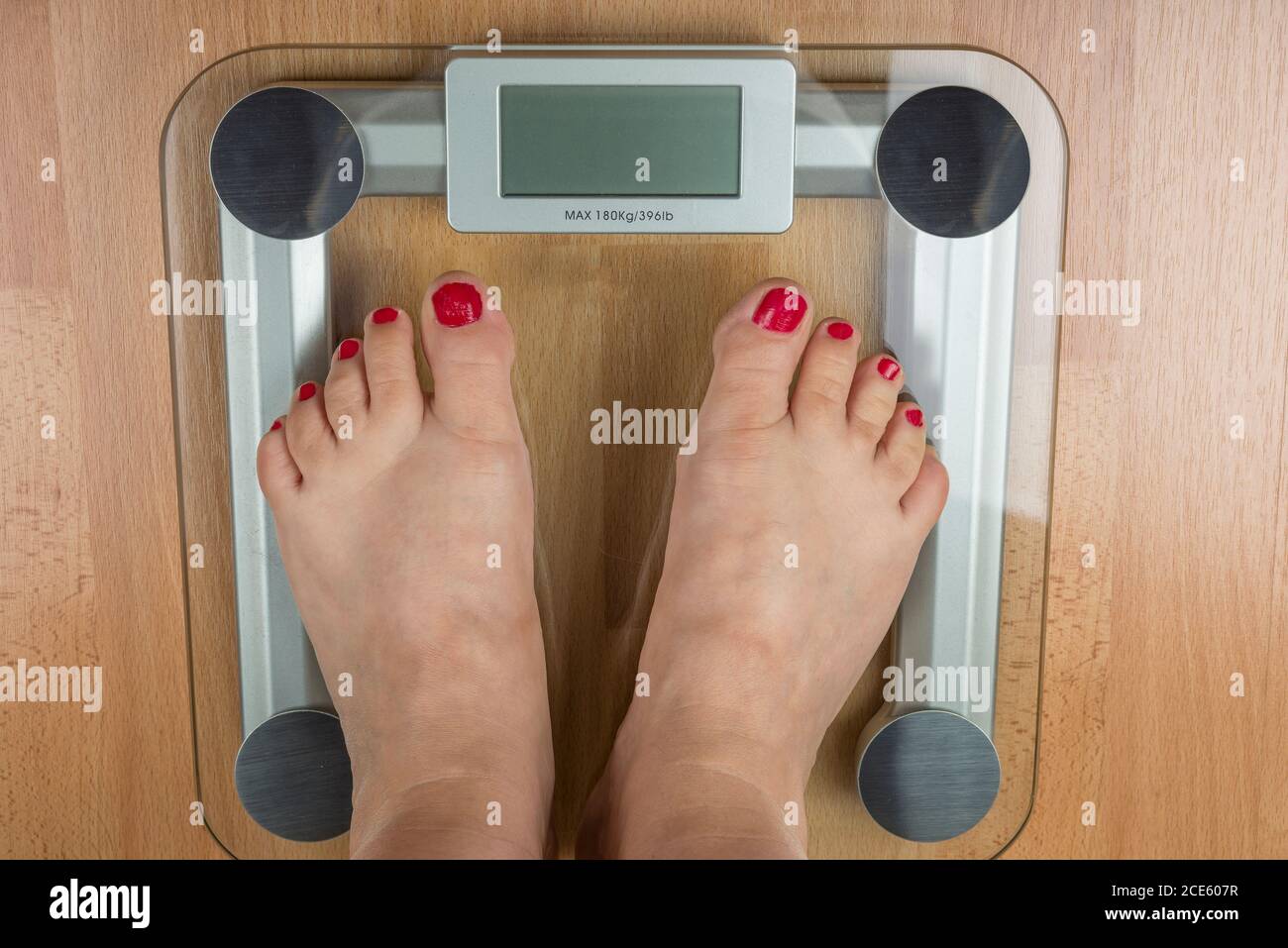 A woman stands with two feet on a scale. Overweight concept Stock Photo ...