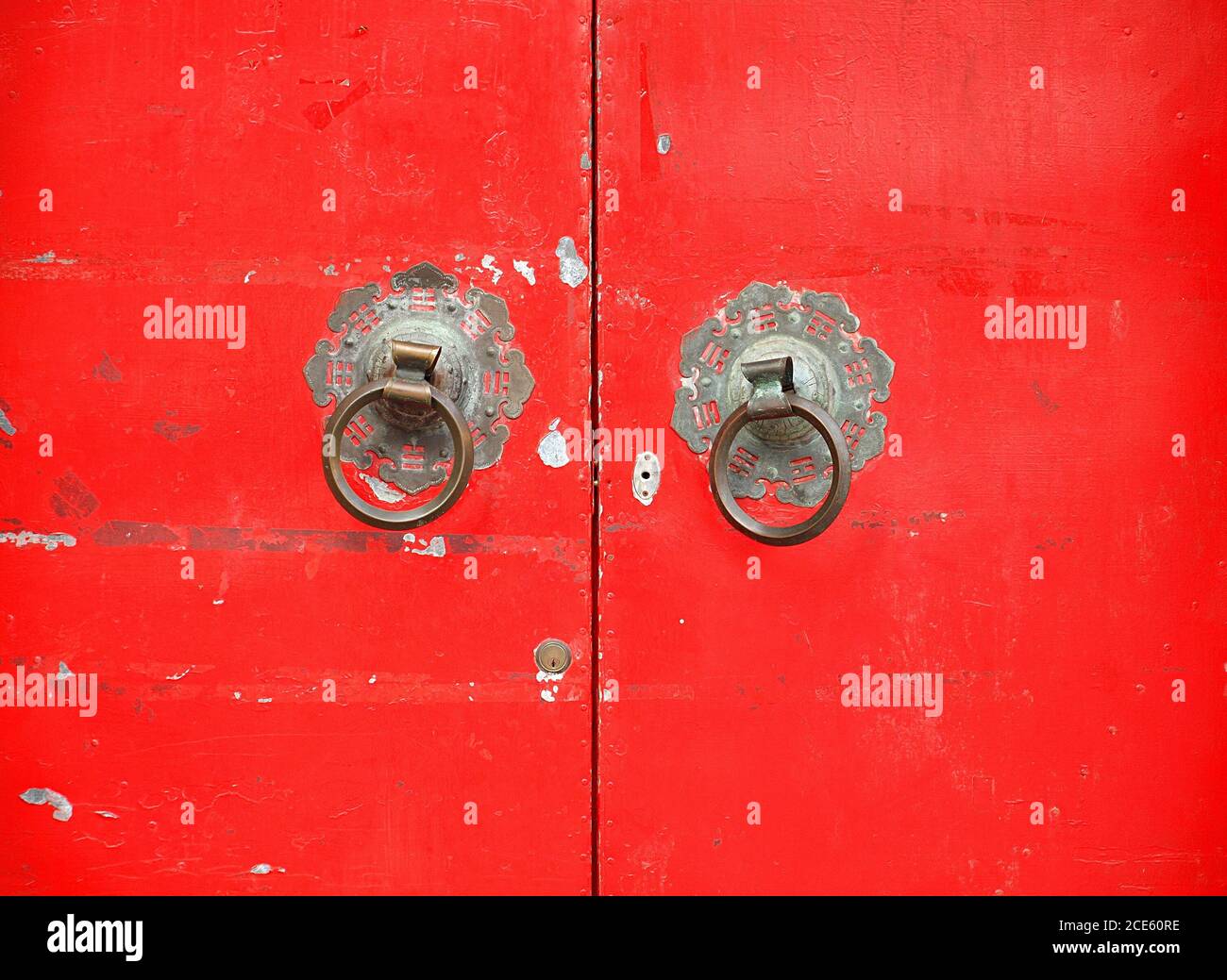 Old red door with bronze doorknockers that show Chinese Taoist symbols ...