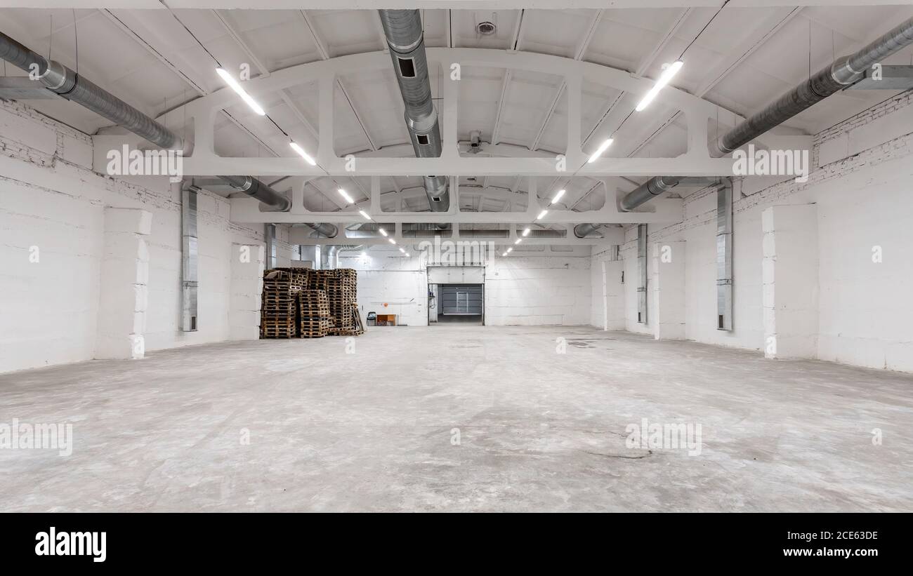 The interior of a huge industrial warehouse made of white bricks with a ...