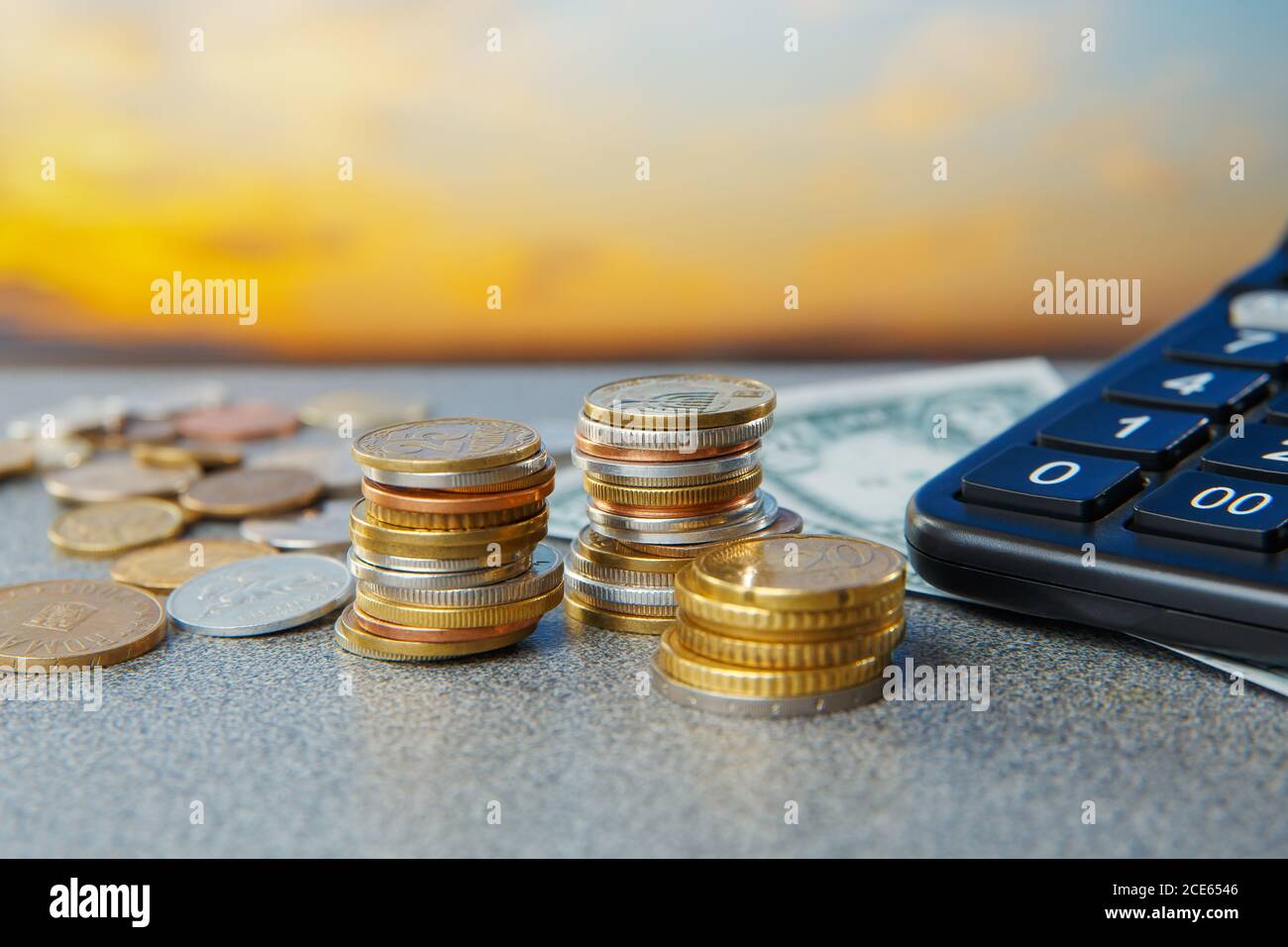 Coins in heaps and a calculator on a sunrise background. High cost ...
