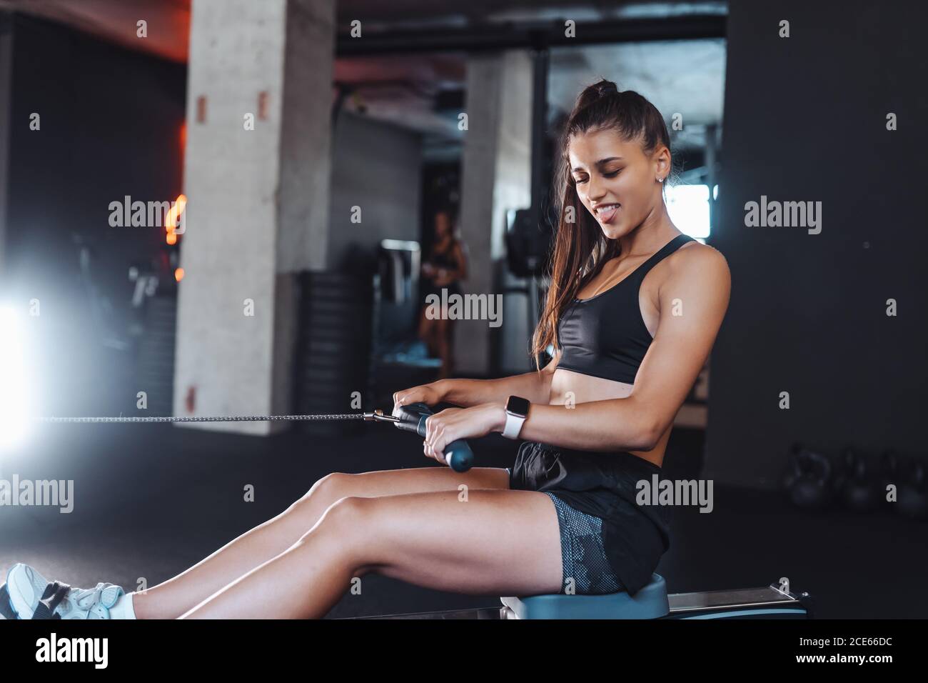 Young woman training and pulling weights in seated cable row machine ...