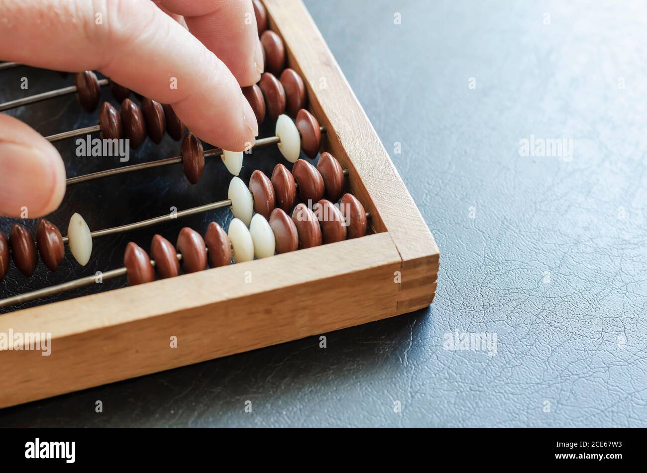 A middle-aged Caucasian man makes calculations on a wooden abacus ...