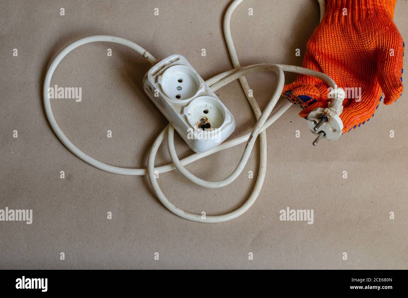 Hand wearing a protective orange glove holds an electrical plug after ...