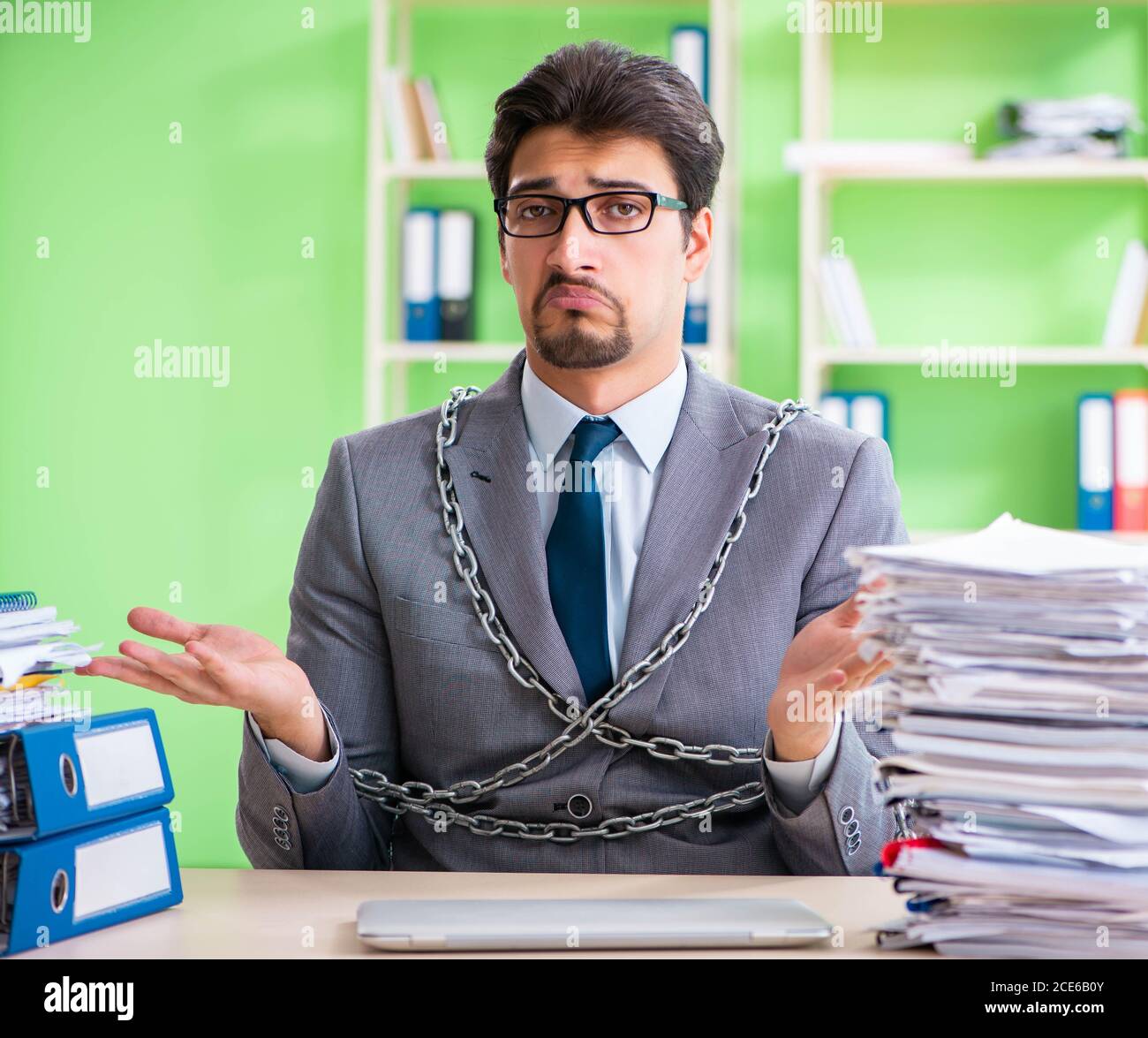 The employee chained to his desk due to workload Stock Photo - Alamy