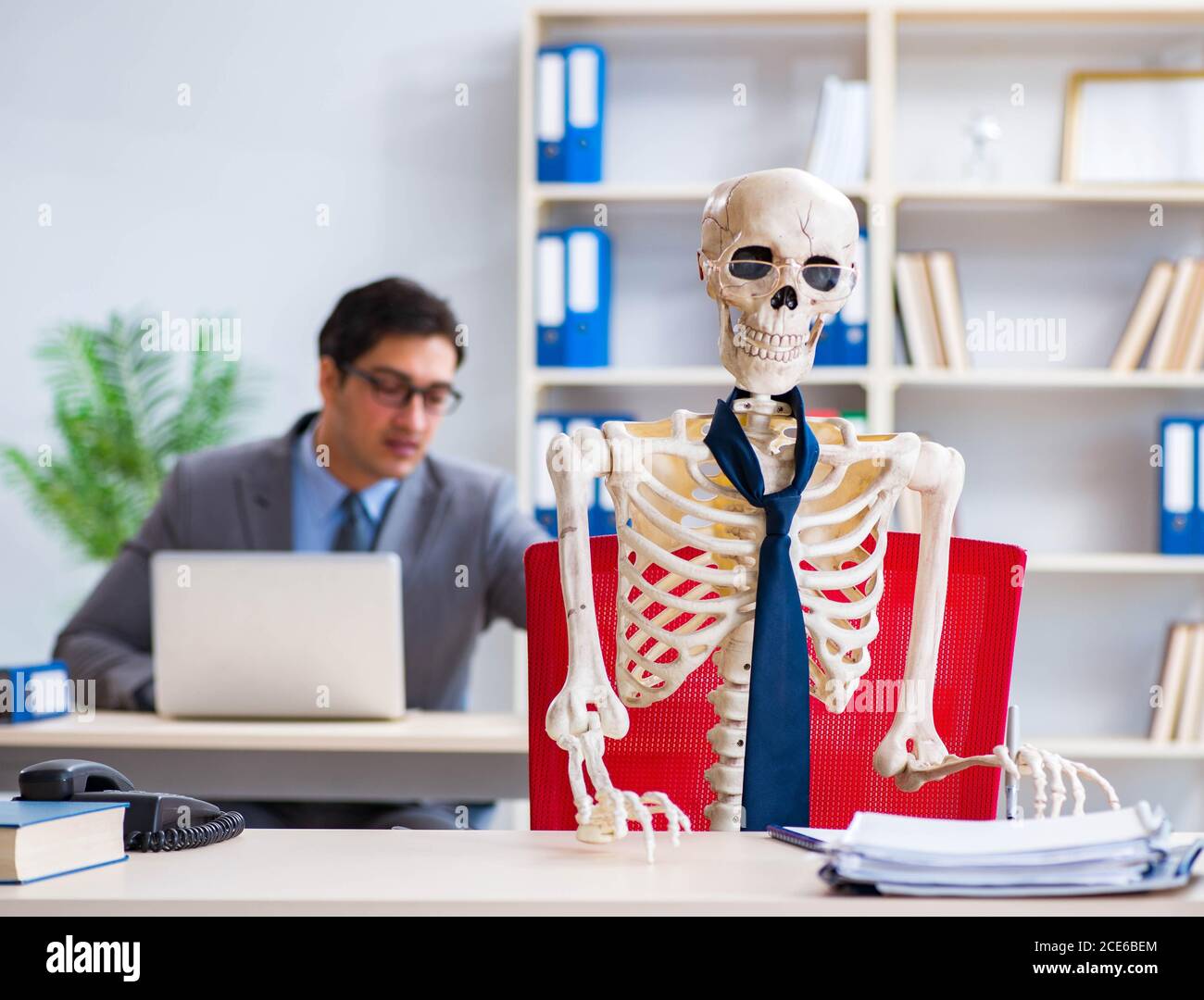 The businessman working with skeleton in office Stock Photo - Alamy