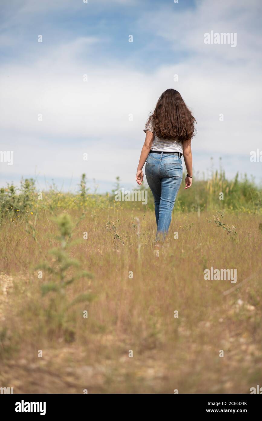 Rear view of teenage girl walking in field Stock Photo - Alamy