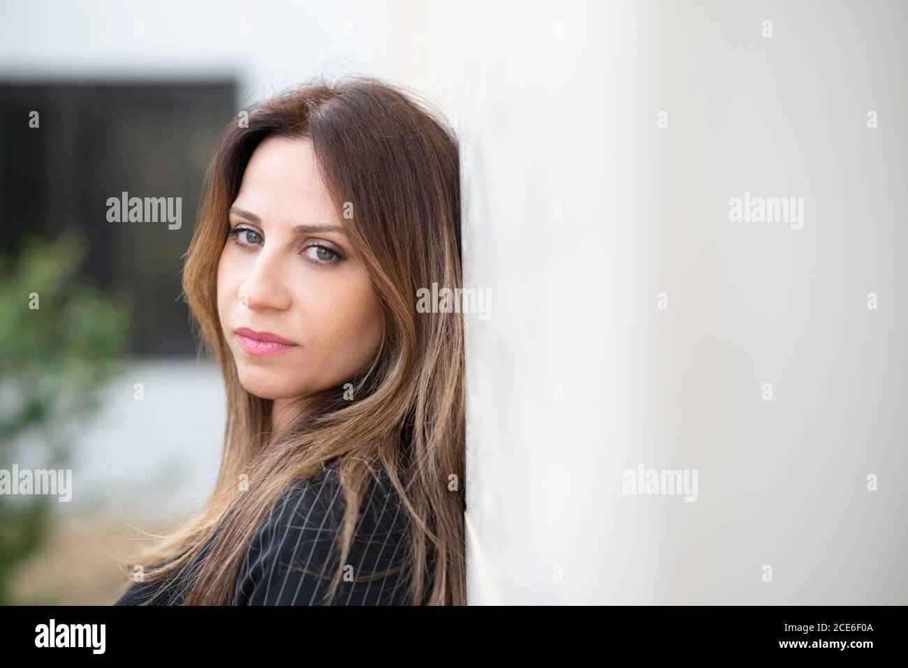 Beautiful woman leaning against the wall Stock Photo - Alamy