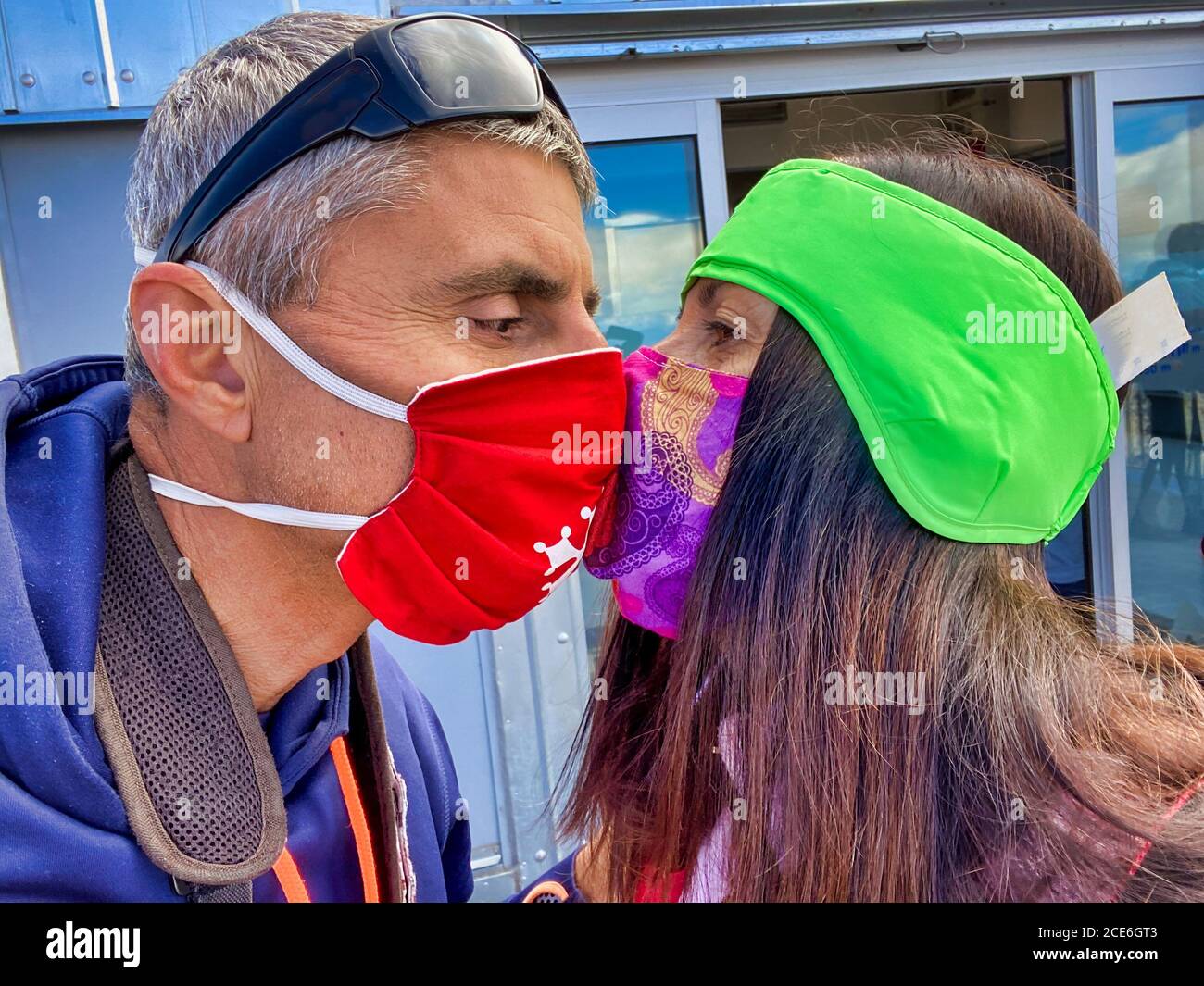 Happy couple kissing each other wearing health face masks during Covid ...