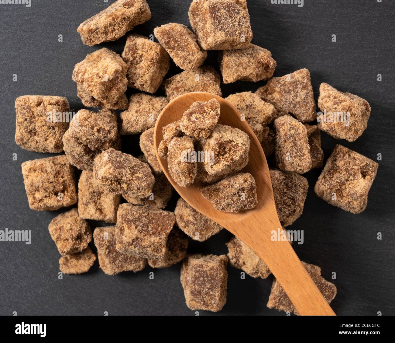 A bird's-eye view of a block of brown sugar and a wooden spoon placed ...