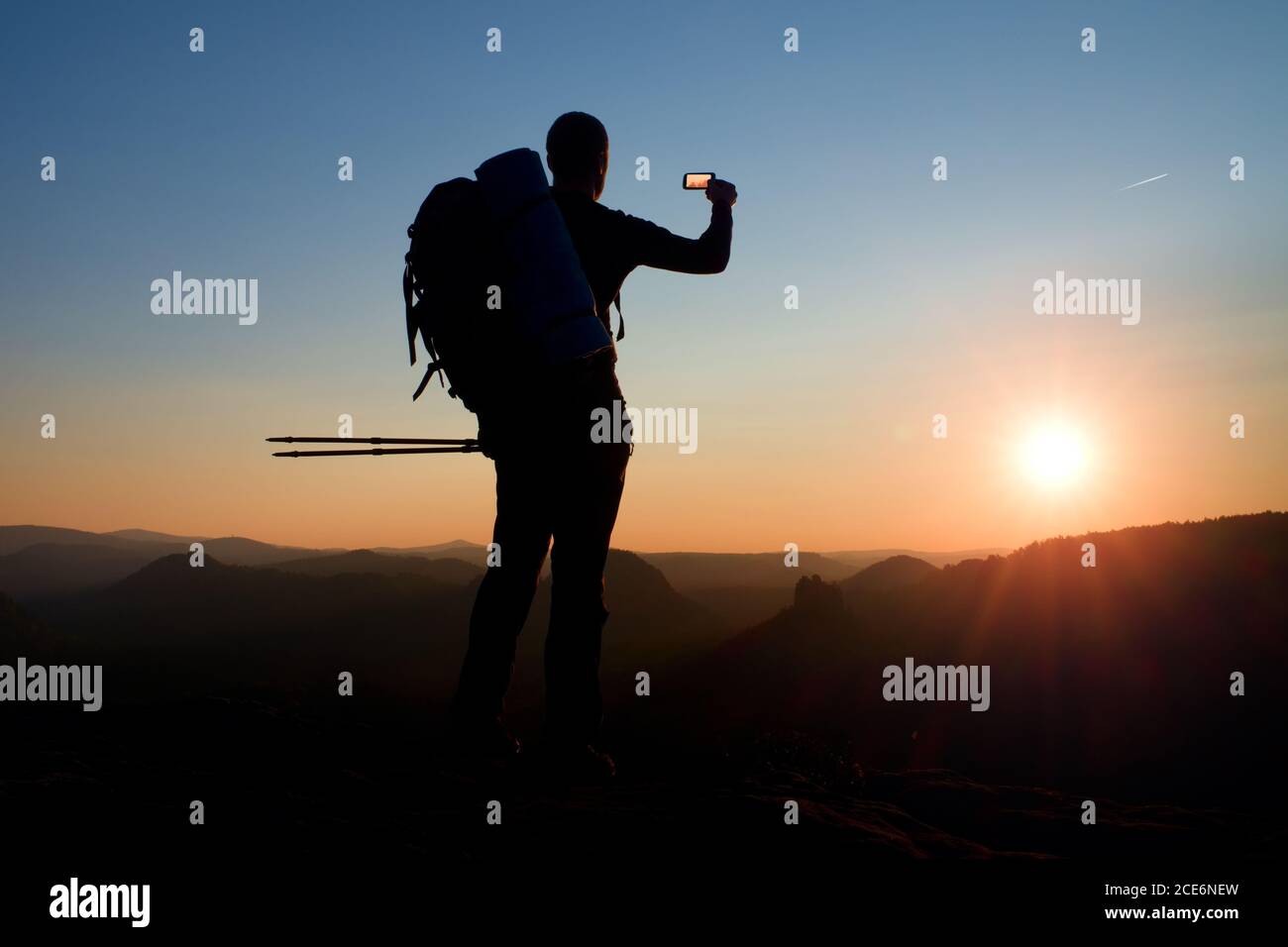 Strong man hiker taking photo with smart phone at mountain peak ...