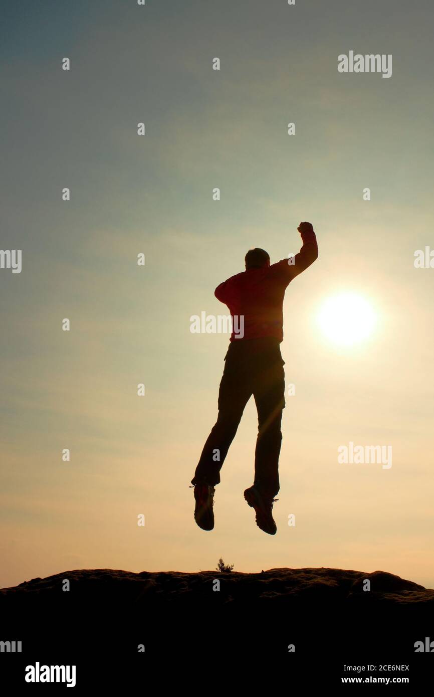 Jumping man. Young crazy man is jumping on colorful sky background ...