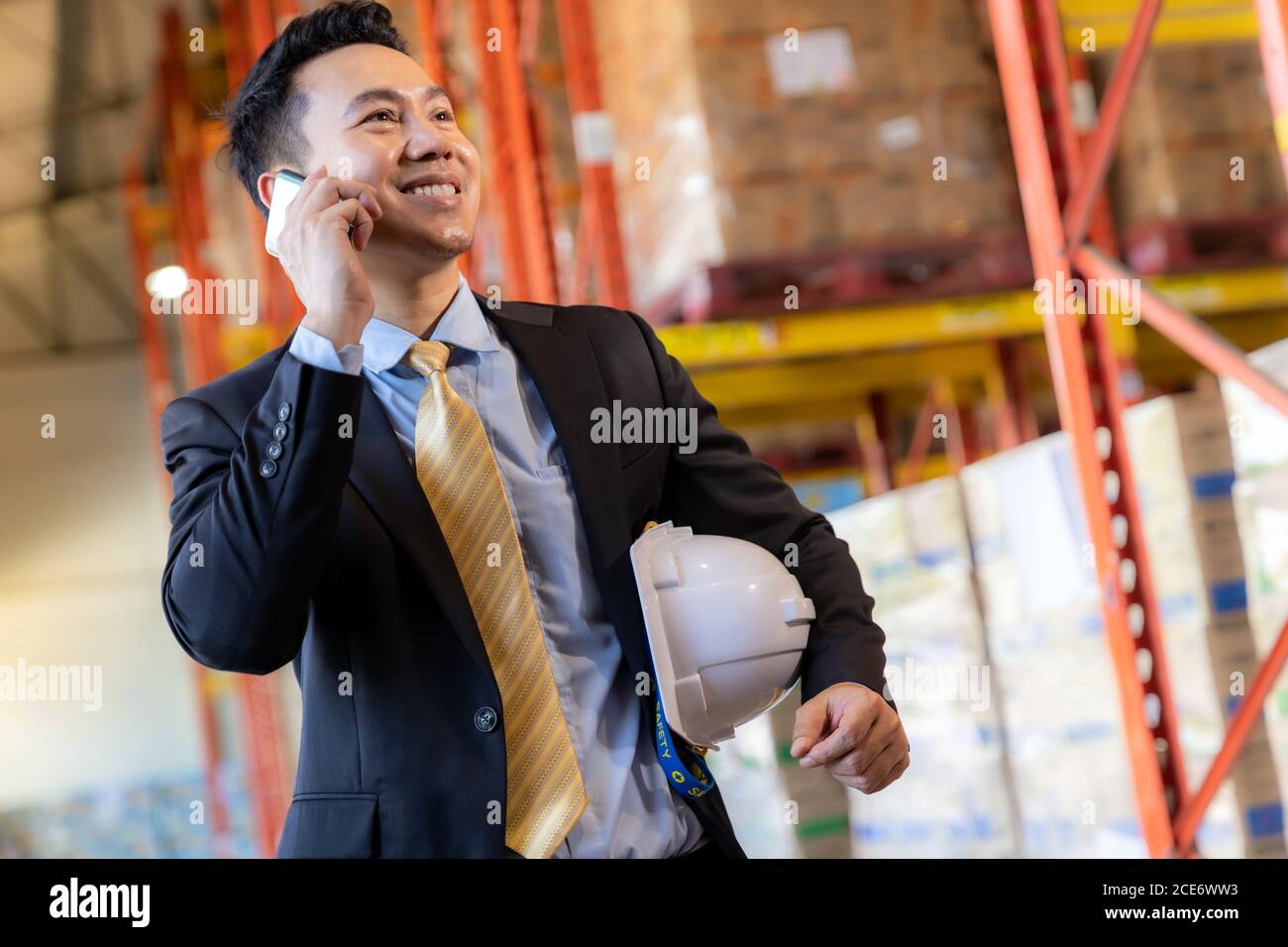 Portrait asian businessman making a call in distribution warehouse ...