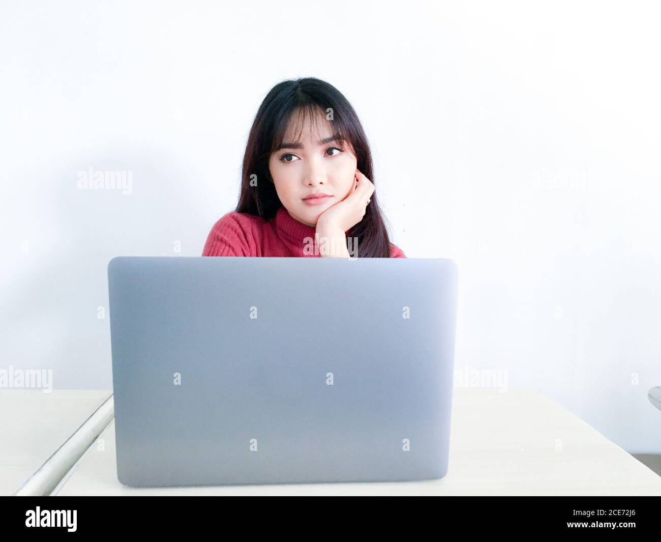 Asian beautiful hair girl is confuse or bored in the front of laptop on ...