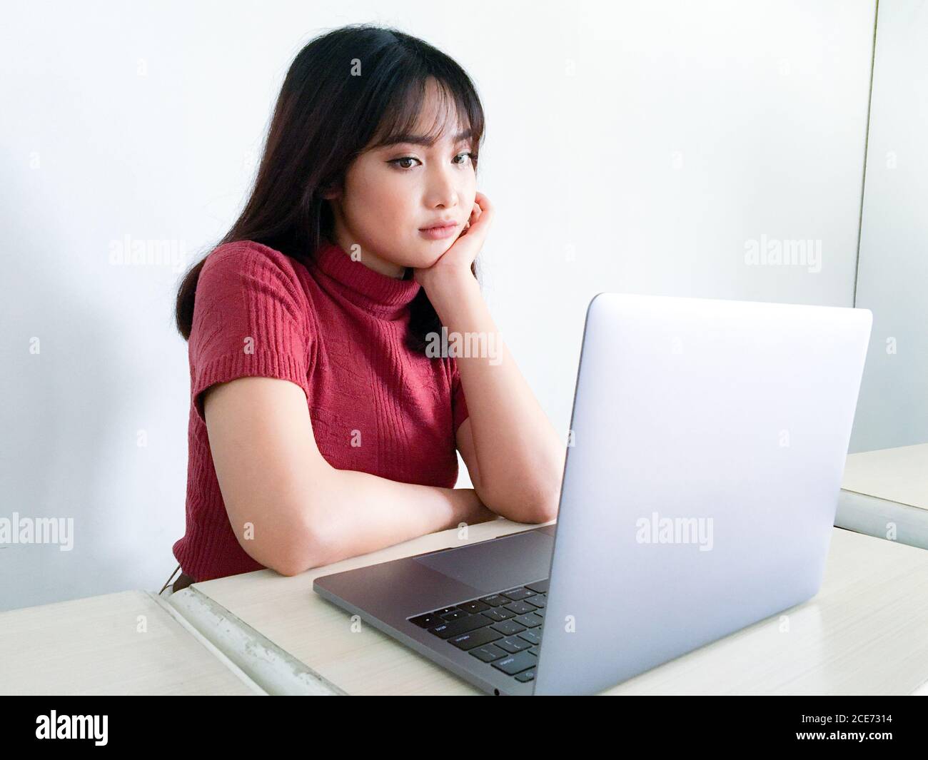 Asian beautiful hair girl is confuse or bored in the front of laptop on ...