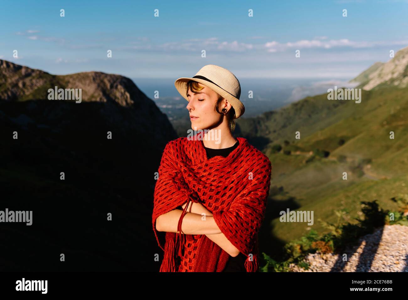 Tranquil female traveler standing on hill and enjoying sun during ...