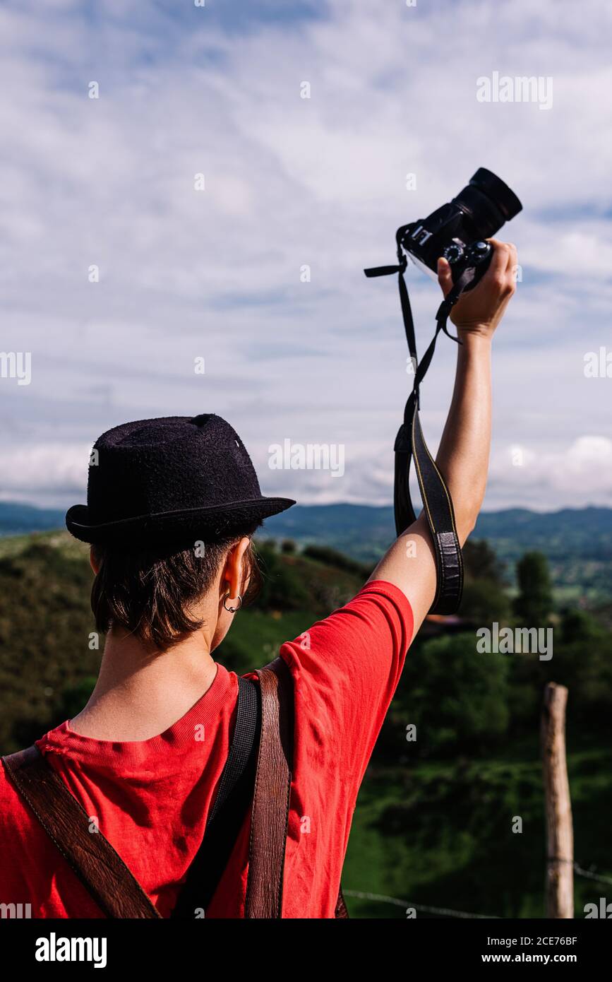 Back view of creative female photographer in stylish clothes standing ...