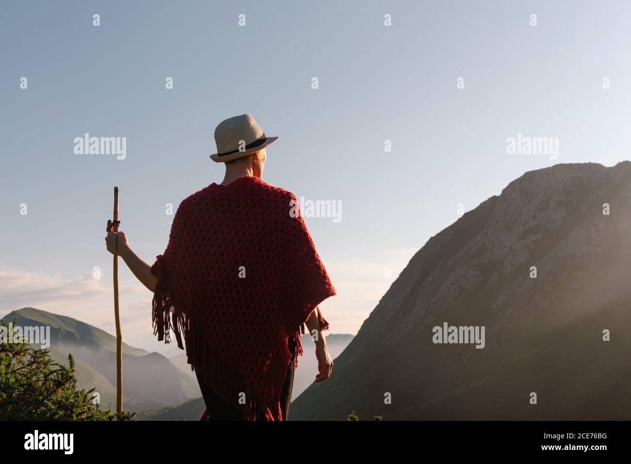 Back view of unrecognizable wanderer with wooden staff enjoying sunrise ...