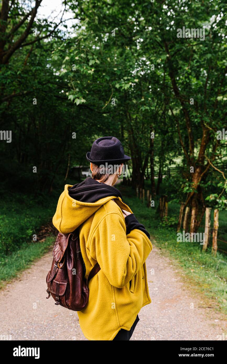 Back view of faceless female traveler with backpack standing along ...