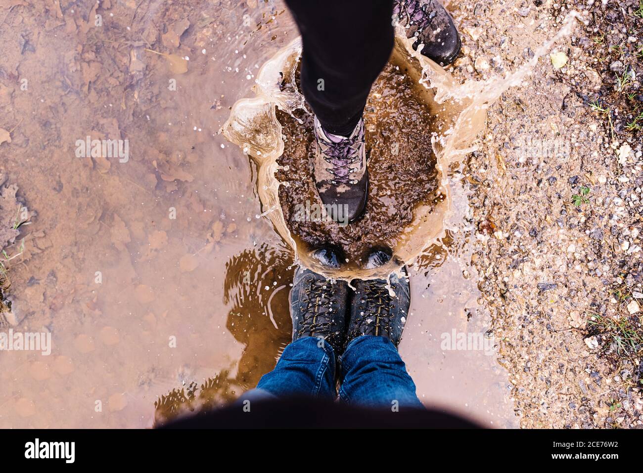 From above of couple of tourists having fun and playing in mud puddle ...